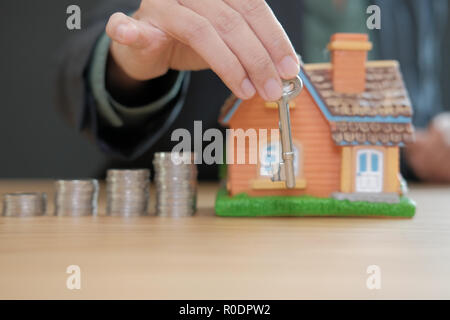 realtor agent with coins stack house model and key. saving money for ...