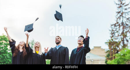 University graduates throwing academic caps up. Graduation day. Happy ...