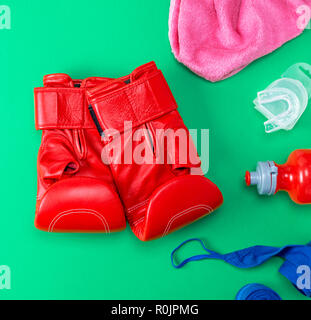 Red leather boxing gloves, water bottle. Sports equipment on a yellow ...