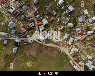 Bird's-eye view from above of a green field, forests in the distance ...