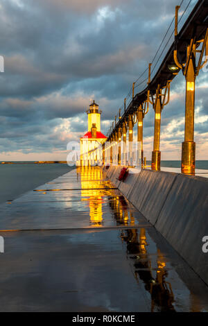 breakwater in the sea with red lighthouse at the end at the sunset with ...