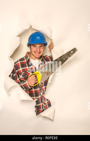 Handsome scary handyman holding in his hands the painting spray gun ...