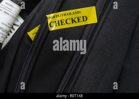 Airline check in luggage tag being attached to a suitcase. Priority ...