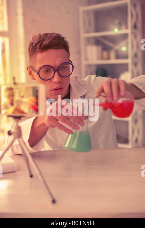 Young funny science man looking in magnifier Stock Photo - Alamy