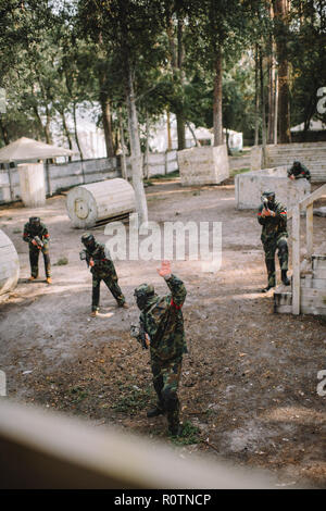 high angle view of paintball player in uniform pointing by hand to his ...