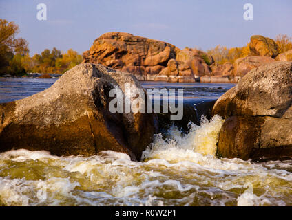 powerful stream of water goes around stone rapids with splashes and ...