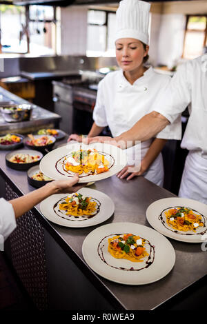 An adult woman in white chef's clothes cooks food in a home kitchen ...