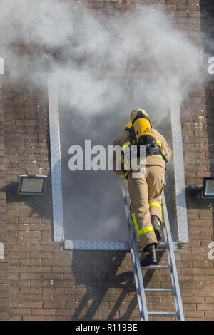A firefighter using ladder access to enter a smoke filled tower during ...