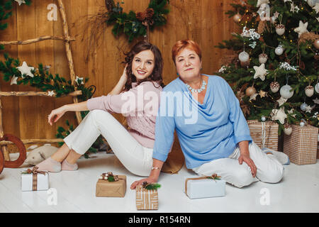 Woman and her senior mother posing near christmas tree Stock Photo - Alamy