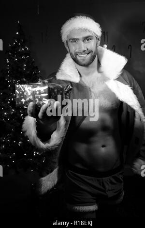 Handsome man with Christmas present and candy cane pinata on light ...