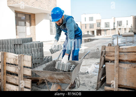 Builder loading paving tiles into the pushcart standing on the ...