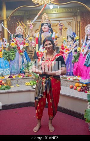 Portrait of a female Hindu Priest in front of a statue of the goddess ...