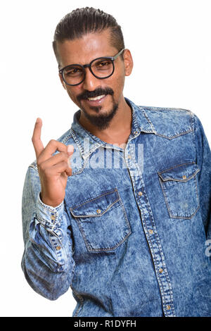 Smiling young man pointing finger looking at copy space on light blue ...