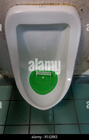 A men's urinal with a soccer (football) net and ball target to ...