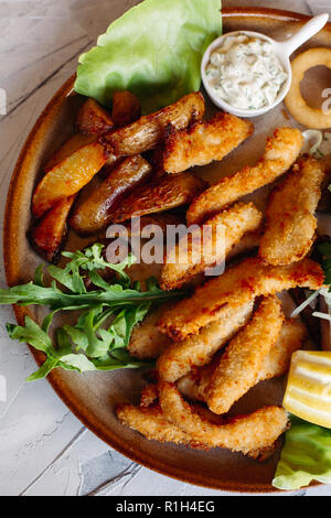 Clay plate full of delicious appetizers standing on white surface Stock ...