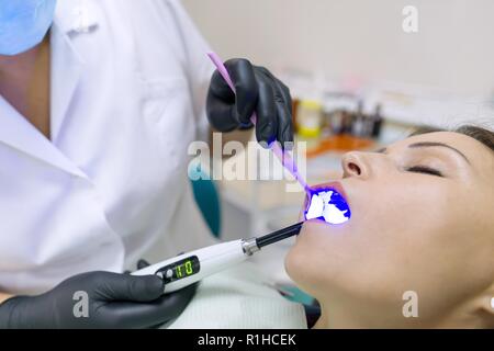 Dentist using dental LED curing light for polymerization of composite ...