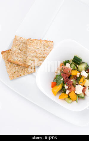Tasty crackers with cheese, tomatoes and cucumber on grey background ...