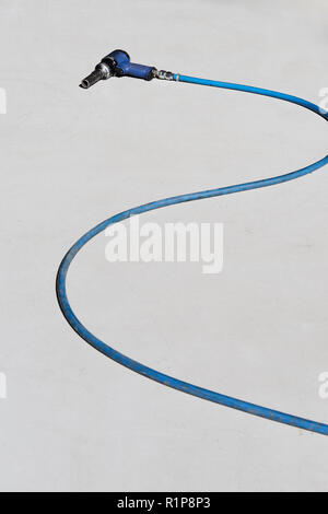 Blue impact wrench rattle gun with air hose on a workshop floor with ...