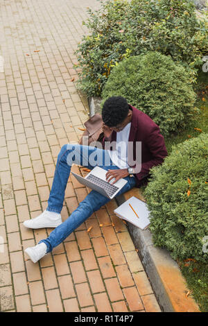 African Male Freelancer Talking On Cellphone Using Laptop At Home Stock Photo - Alamy