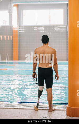 Rear view of muscular male swimmer on beach bending over sideways Stock ...
