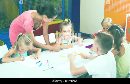 Glad kids drawing on lesson in elementary school class with help of ...