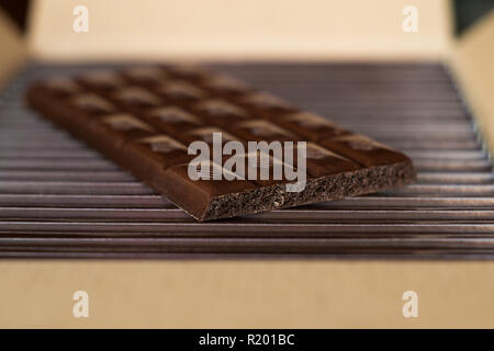 Tiles of dark chocolate on a cardboard box packed with chocolate. Close ...