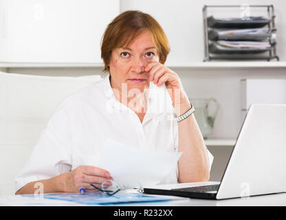 Aged woman worker facing challenge in project in office Stock Photo - Alamy
