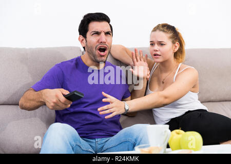 Young couple arguing because of TV remote control sitting on couch ...
