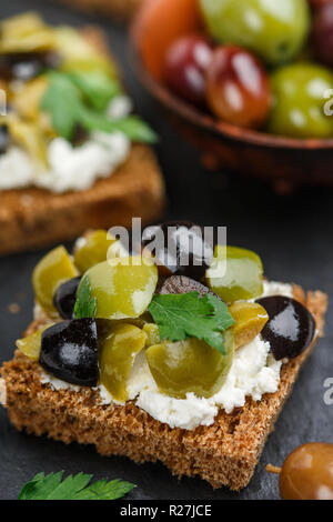 Rye bread toast (canape) with black and green olives, feta cheese and ...