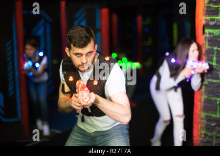 Excited guy aiming laser gun at other players during lasertag game in ...