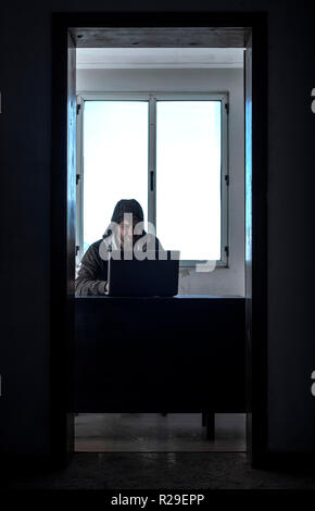 Hacker in a room with illuminated window Stock Photo - Alamy