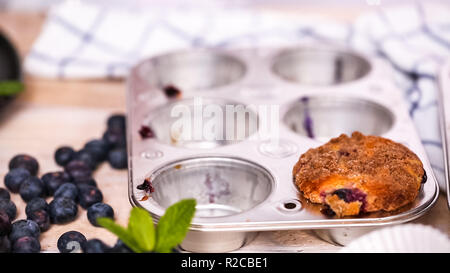 Taking blueberry muffins out of metal muffin pan Stock Photo - Alamy