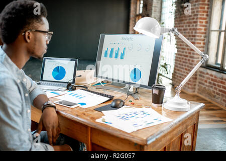 Young african man working with analitycs sitting at the beautiful ...