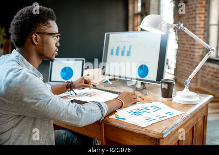 Young african man working with analitycs sitting at the beautiful ...