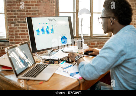 Young african man working with analitycs sitting at the beautiful ...