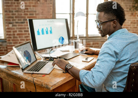 Young african man working with analitycs sitting at the beautiful ...