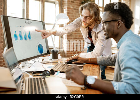 Two male coworkers working with analitycs in the beautiful office with ...