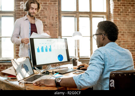 Two male coworkers working with analitycs in the beautiful office with ...