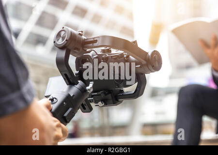 Videographer using gimbal stabilizer with camera on black background ...