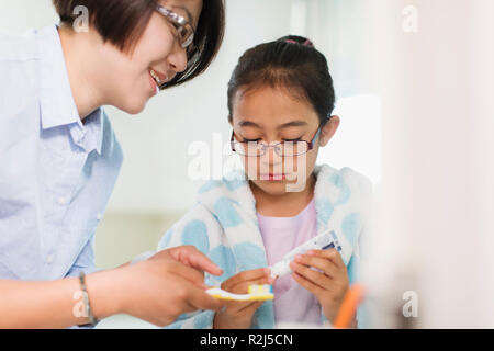 Mother teaching asian girl use toothbrush to clean, suffers from pain ...