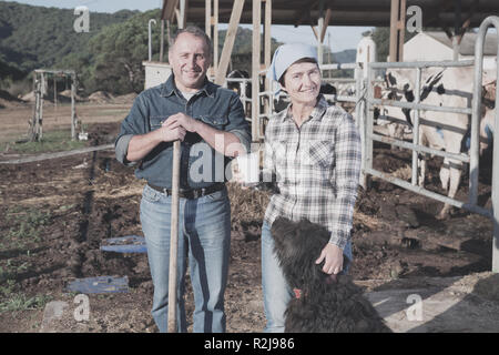 Couple farmers are standing with dog Stock Photo - Alamy