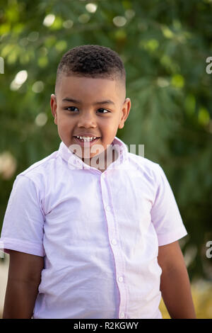 Adorable latin child in the garden with a beautiful green of background ...