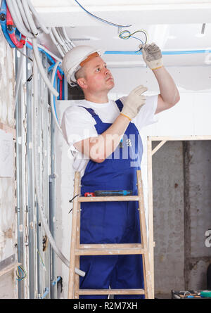 Professional builder engaged in electrical installation work at indoors ...