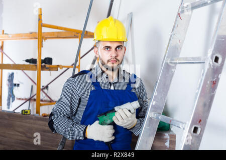 positive young british builder is ready to work with a dril at the ...