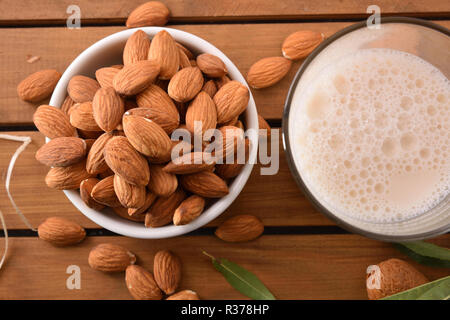 Almond drink in a glass cup on a wooden table in the field with almond ...