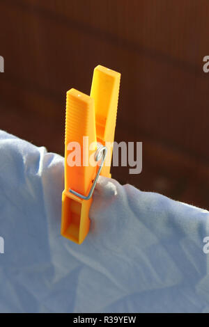 Detail of a blue clothes peg holding freshly washed laundry on a ...