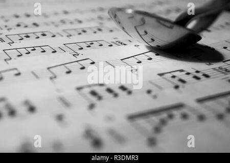 A closeup of a mirror reflecting music notes in the book, with lilac ...