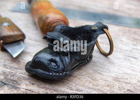 Colorfull leather key ring in the shape of old shoe on wooden ...