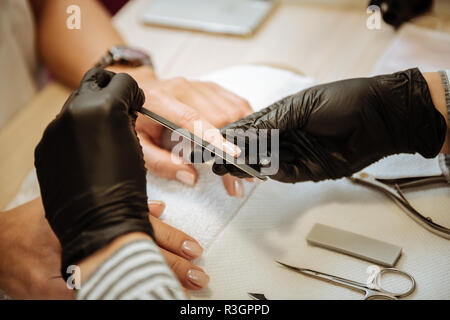 Dark-haired nail artist making manicure for businesswoman Stock Photo ...