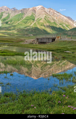 A bridge over a river with its image reflecting in the water, in a ...